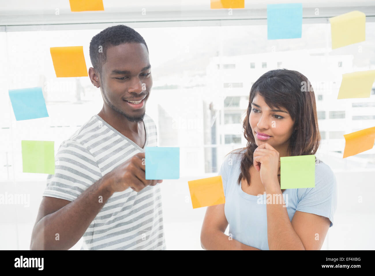 Smiling coworker reading sticky notes Stock Photo - Alamy