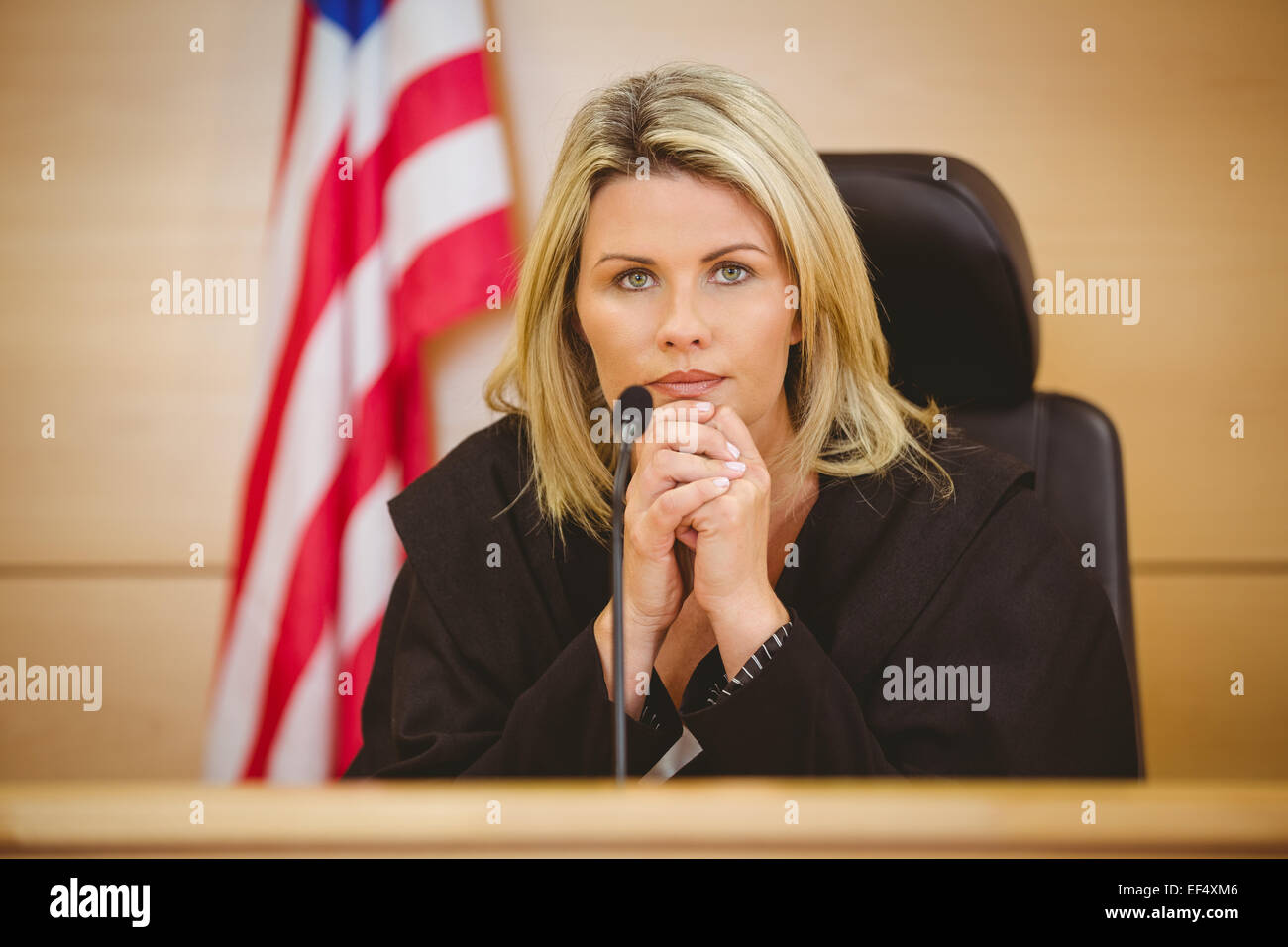 Portrait of a serious judge with american flag behind her Stock Photo ...