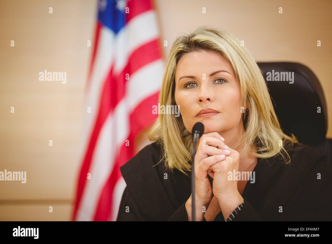 Portrait of a serious judge with american flag behind her Stock Photo ...