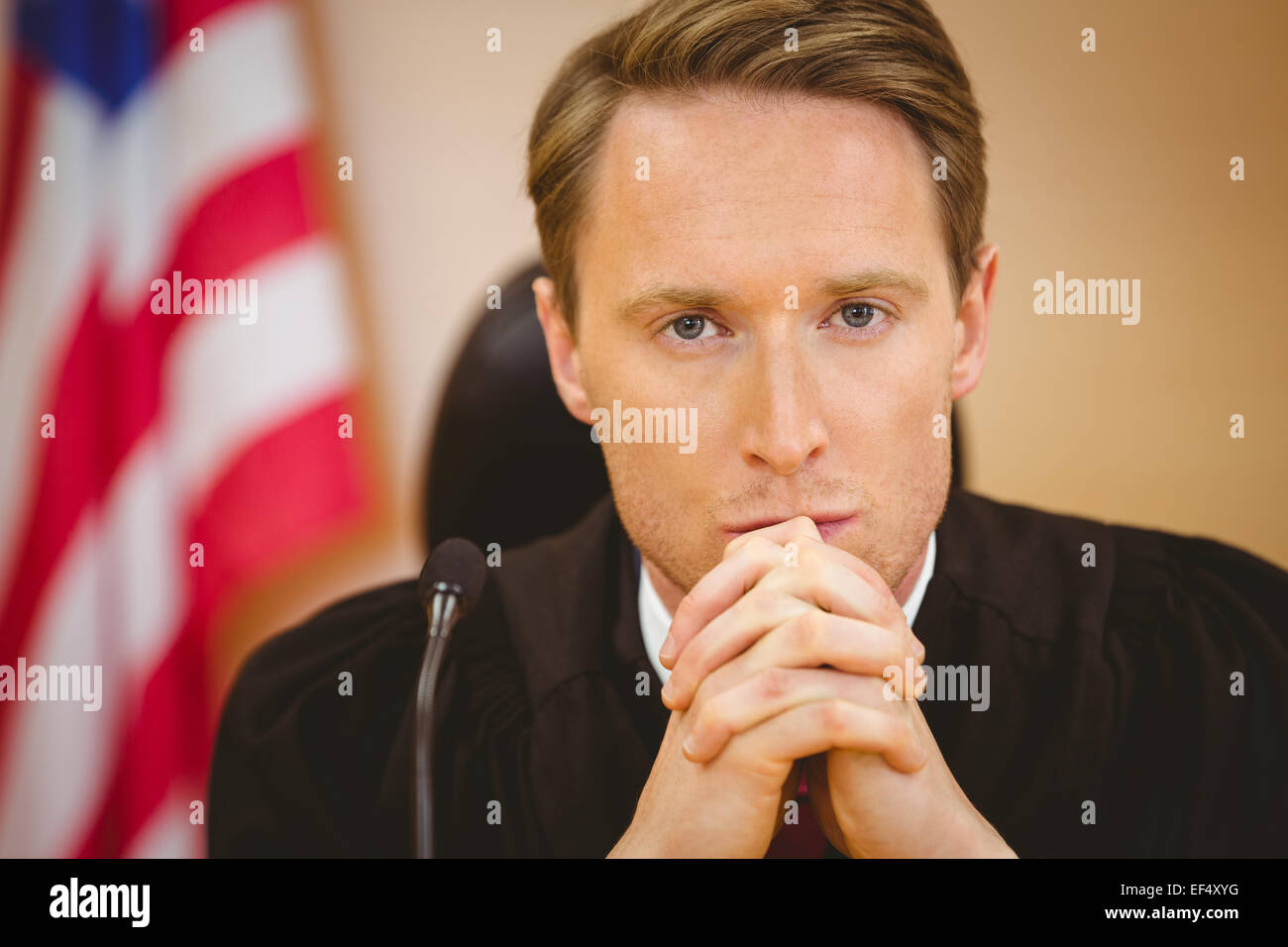 Unsmiling judge with american flag behind him Stock Photo - Alamy