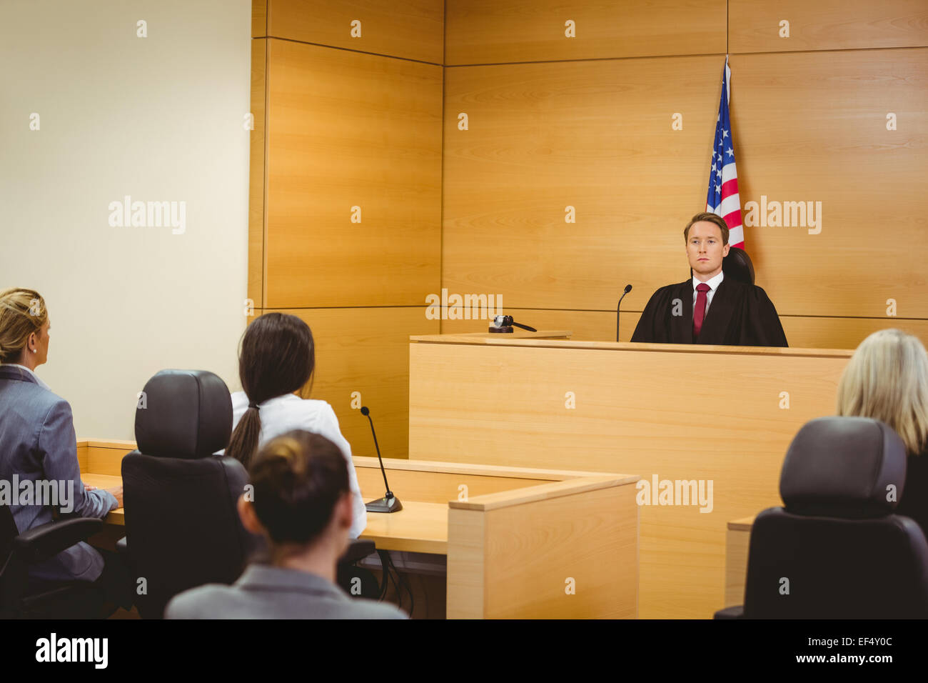 Unsmiling judge with american flag behind him Stock Photo - Alamy