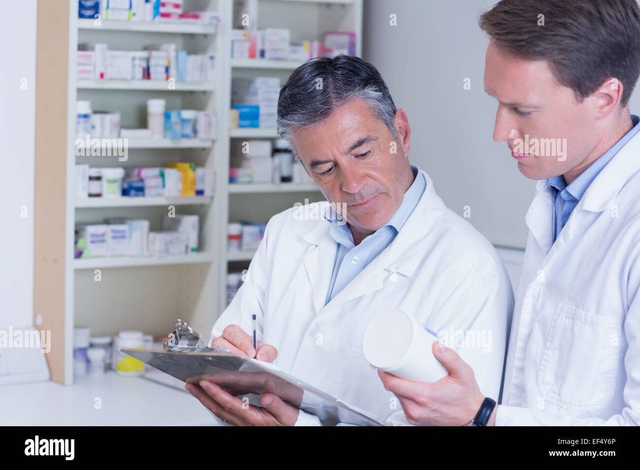 Man holding medication and his colleague writing a prescription Stock ...