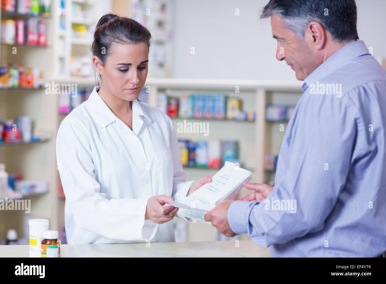 Customer handing a prescription to a trainee Stock Photo - Alamy