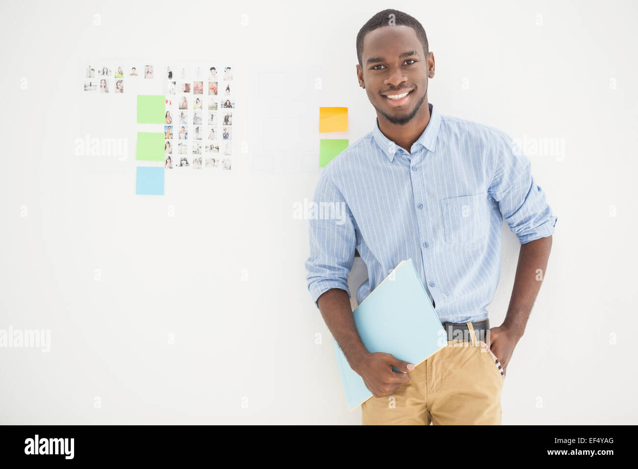 Smiling businessman standing and holding file Stock Photo - Alamy