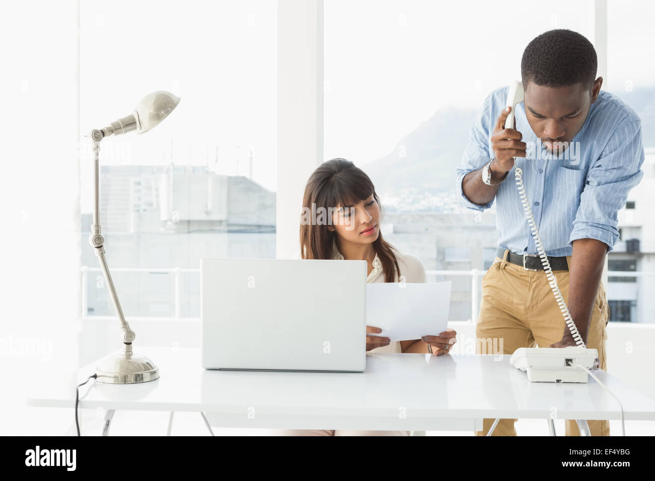 Serious businessman phoning near his colleague Stock Photo - Alamy
