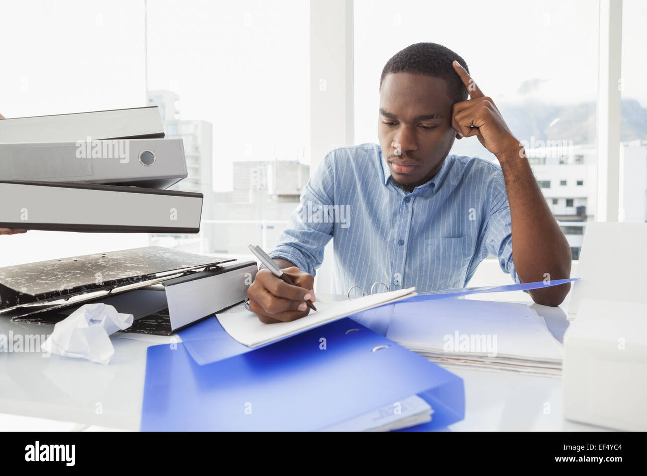 Tired businessman writing notes at desk Stock Photo - Alamy
