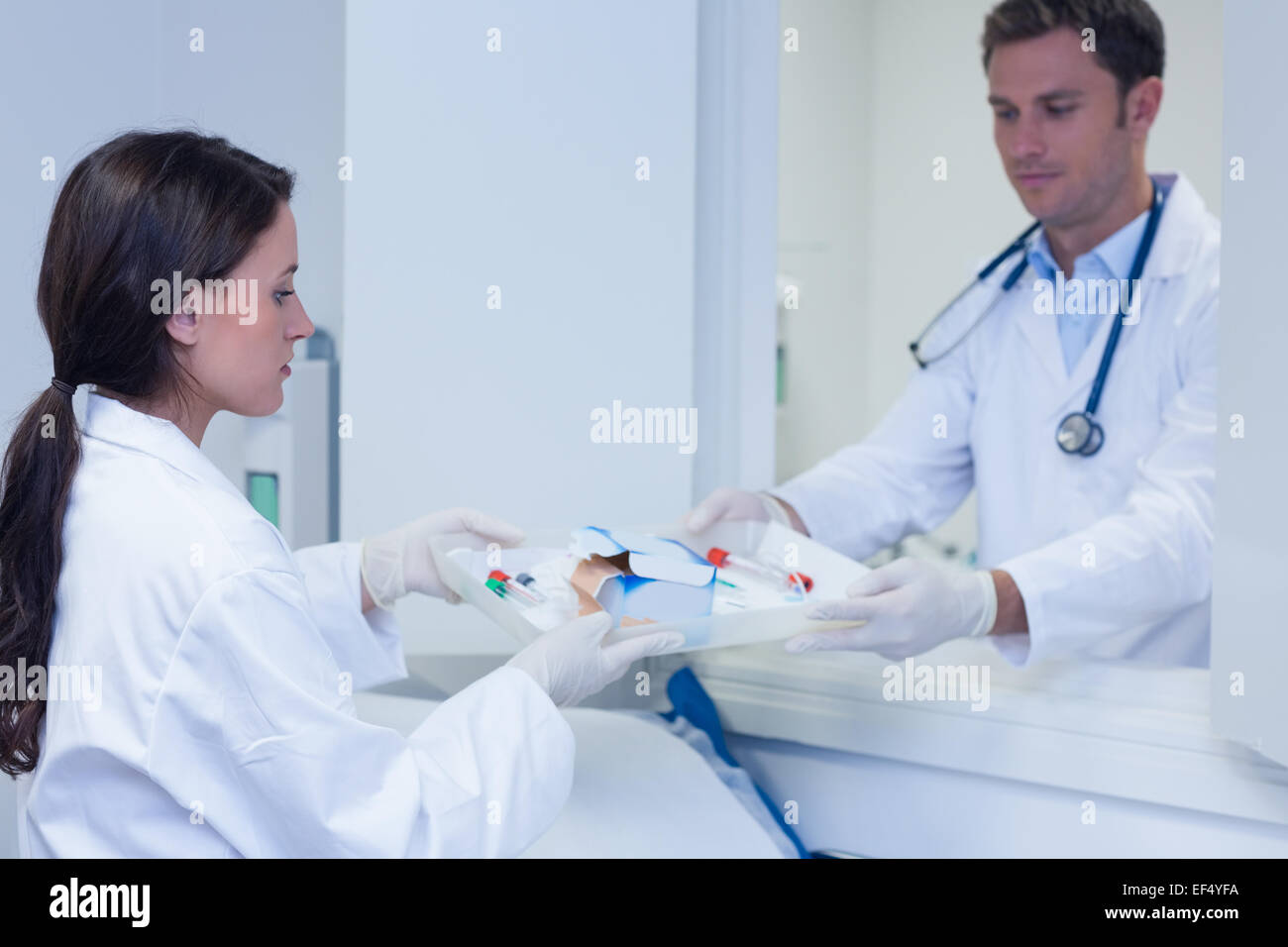 Doctor giving tray with blood sample to his colleague Stock Photo - Alamy