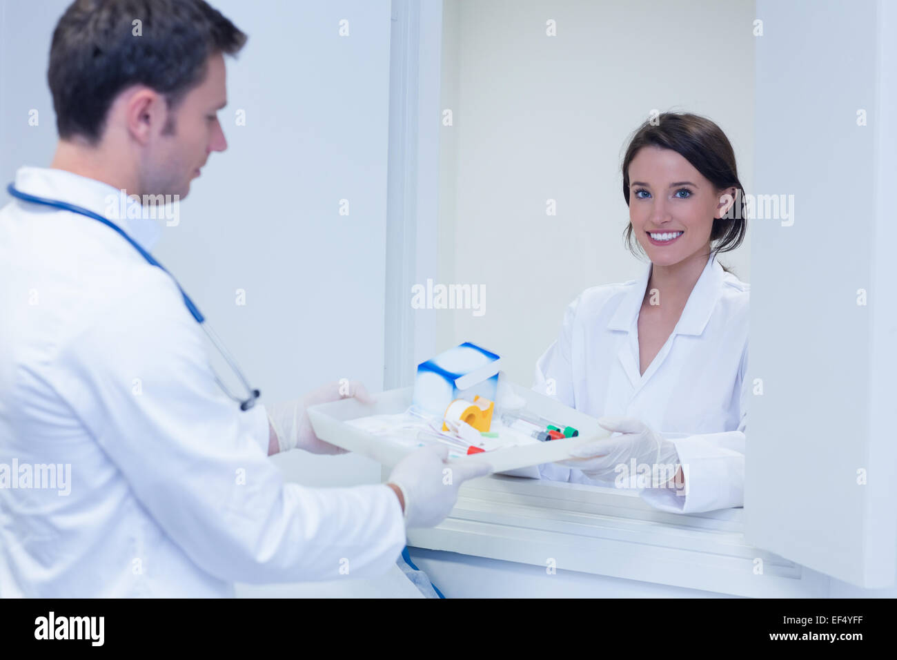 Portrait of a smiling woman taking tray with blood samples Stock Photo ...
