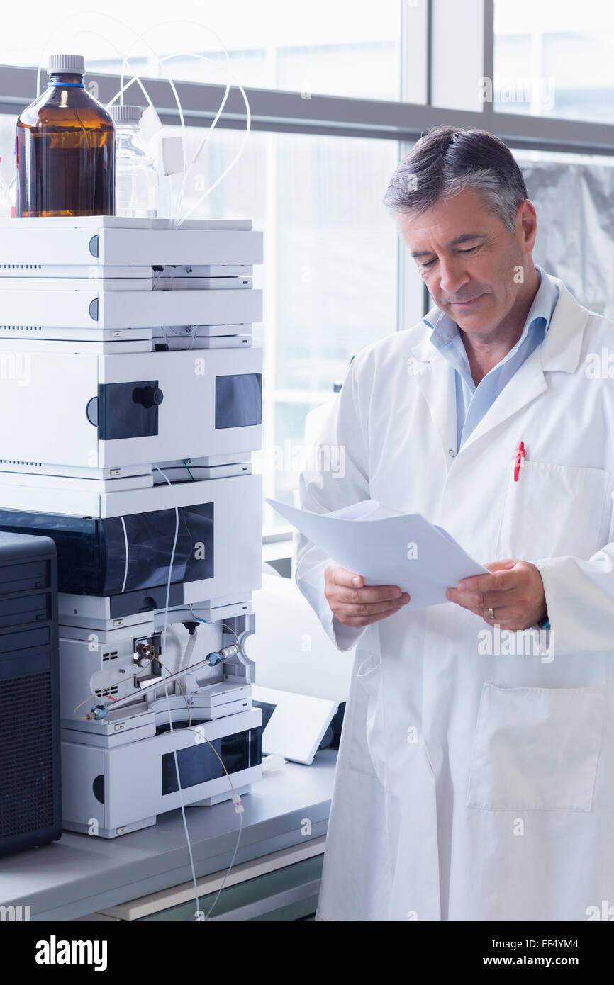 Scientist standing in lab coat reading analysis Stock Photo - Alamy