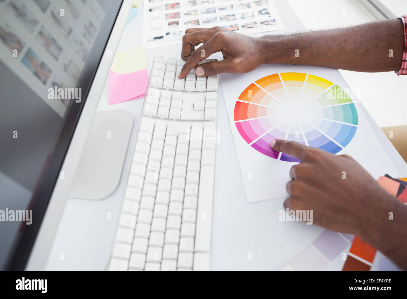 Designer using a colour wheel and typing on keyboard Stock Photo - Alamy