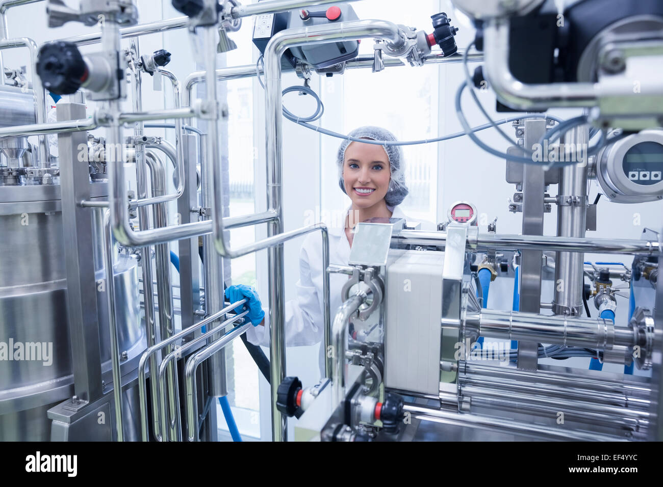 Portrait of a smiling scientist behind metal pipe Stock Photo - Alamy