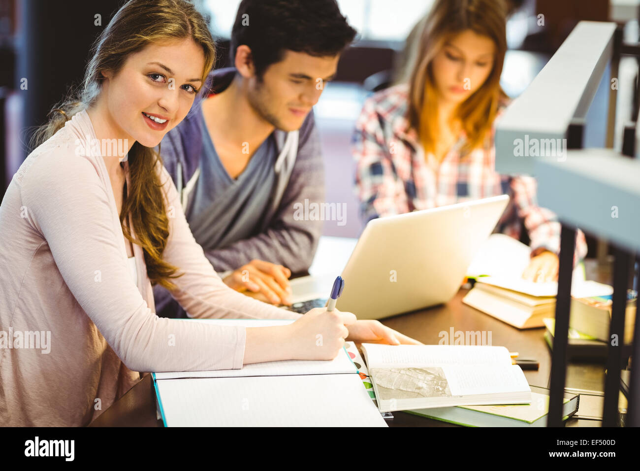 Happy student writing on her notepad smiling at camera Stock Photo - Alamy