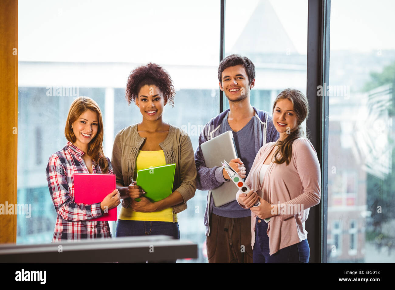 Four smiling classmates standing in front of the window Stock Photo - Alamy