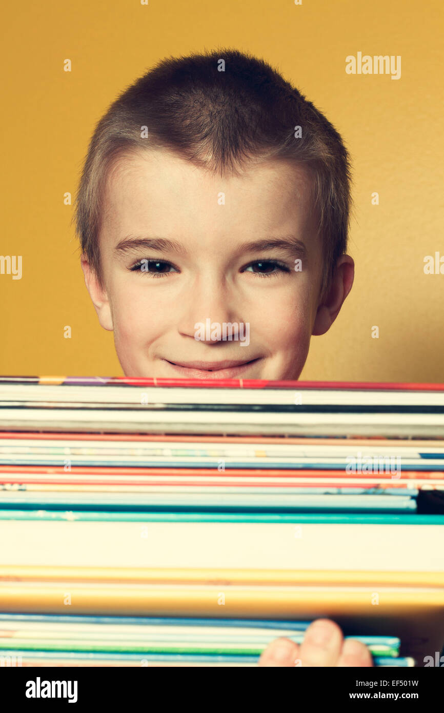 Young boy indoors carrying a stack of books Stock Photo - Alamy