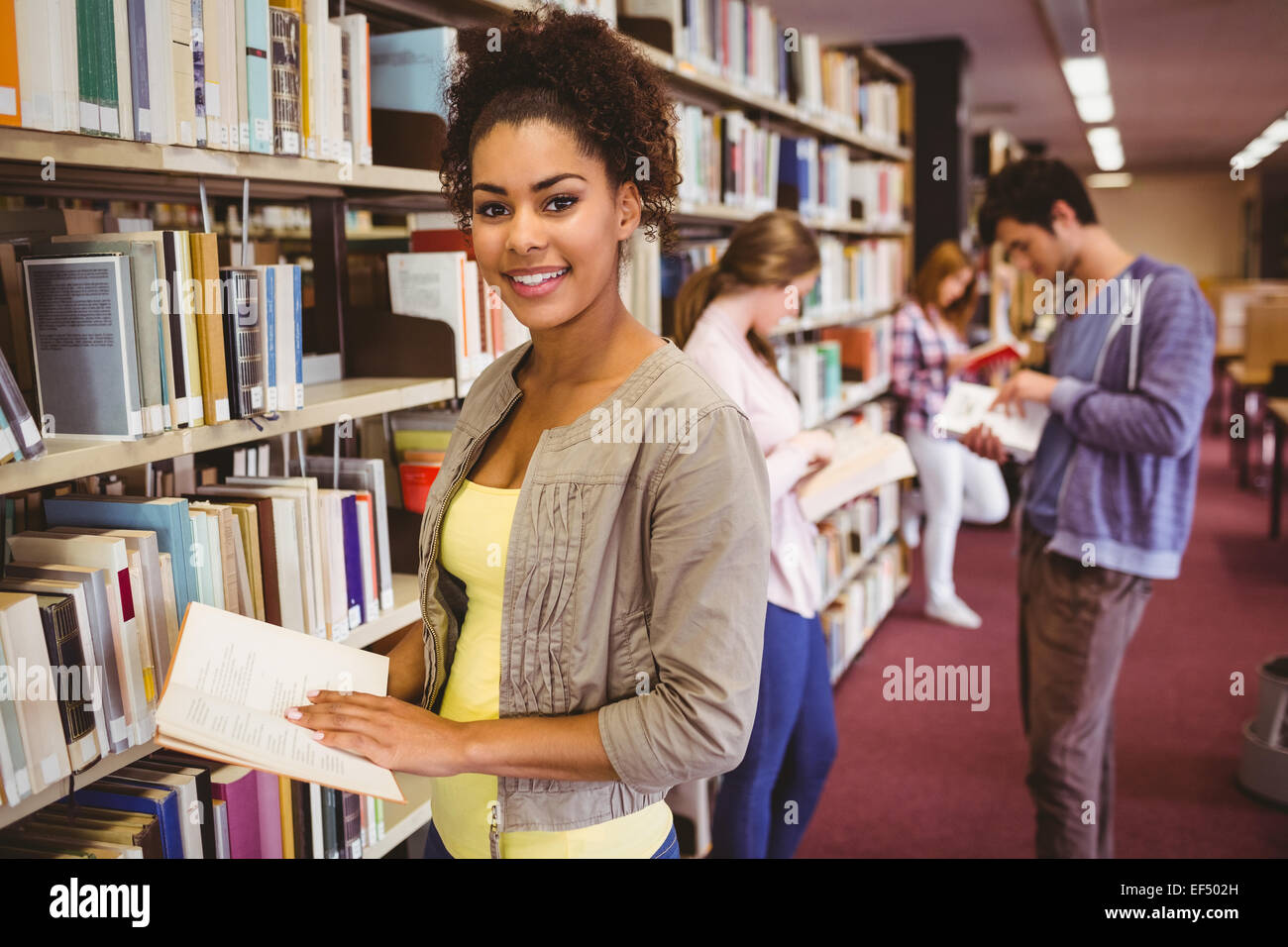 Happy student taking book from shelf Stock Photo - Alamy