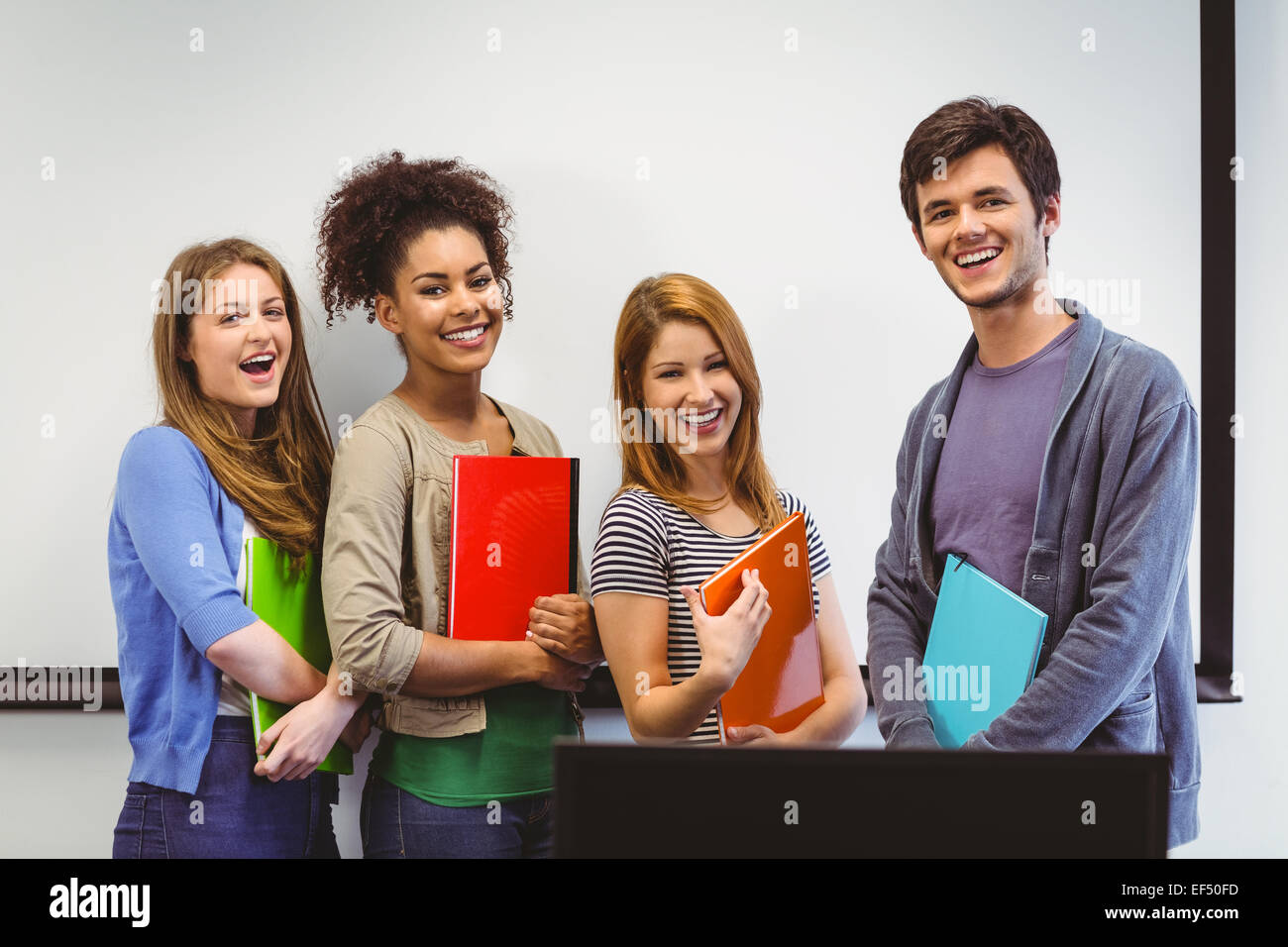 Students standing and smiling at camera holding notepads Stock Photo ...