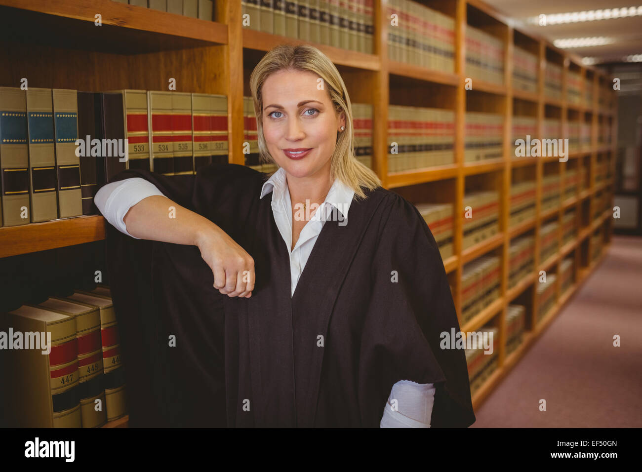Smiling lawyer leaning on shelf Stock Photo - Alamy