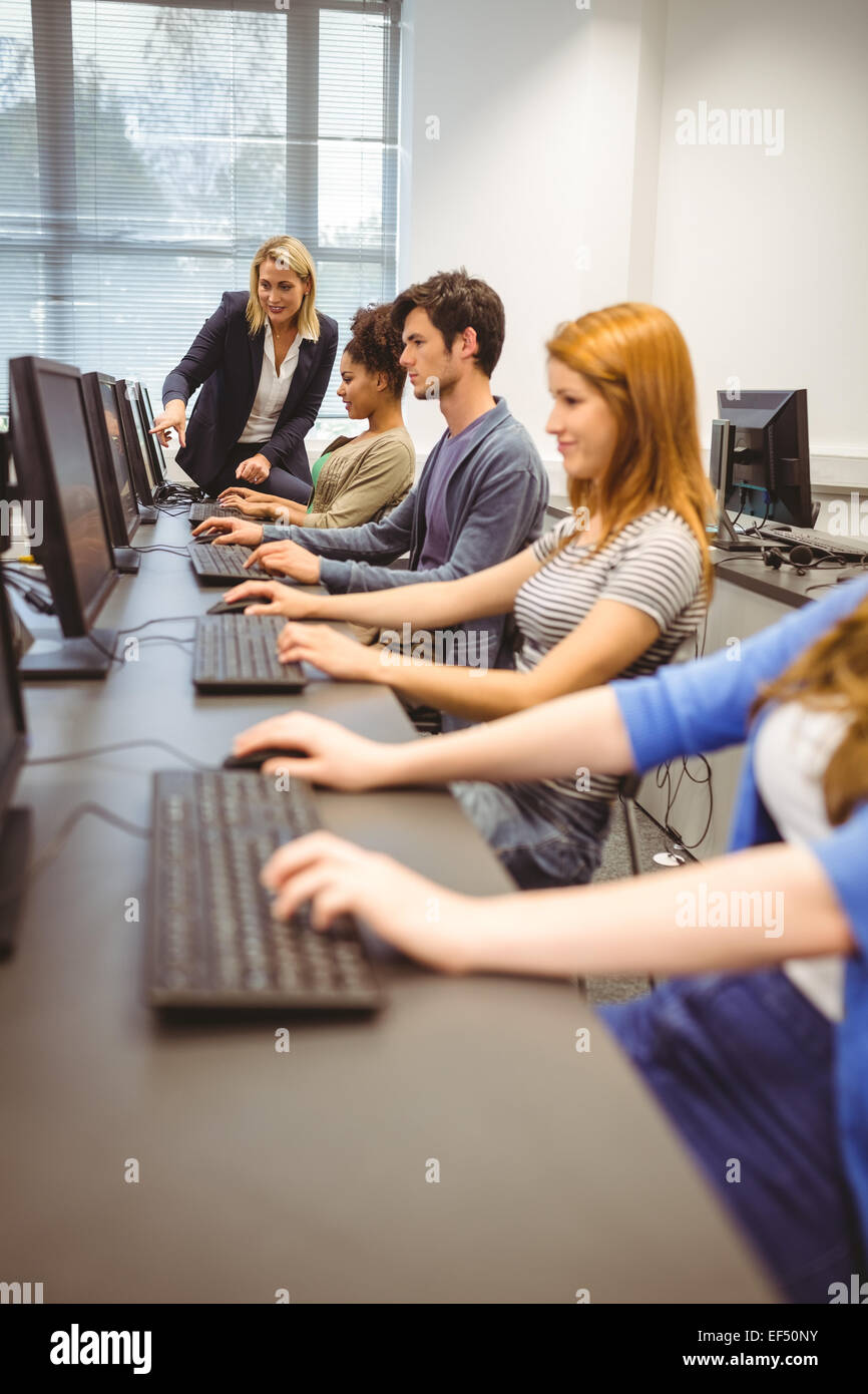 Computer teacher helping a pretty student in her class Stock Photo - Alamy