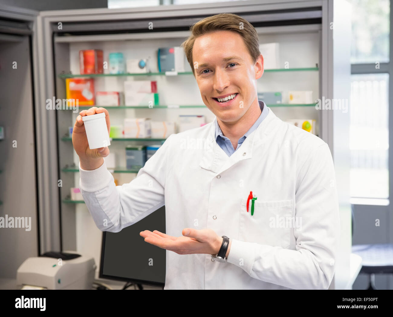 Handsome pharmacist showing medicine jar Stock Photo - Alamy