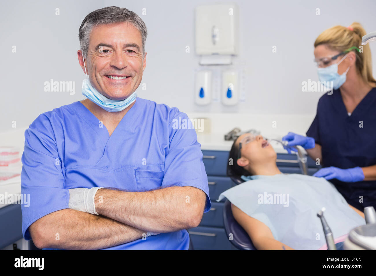 Portrait of a smiling dentist his arms crossed Stock Photo - Alamy
