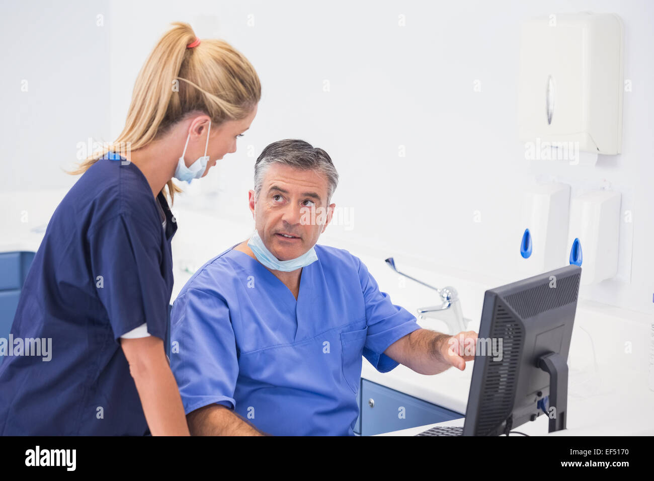 Co-workers using computer and talking Stock Photo - Alamy