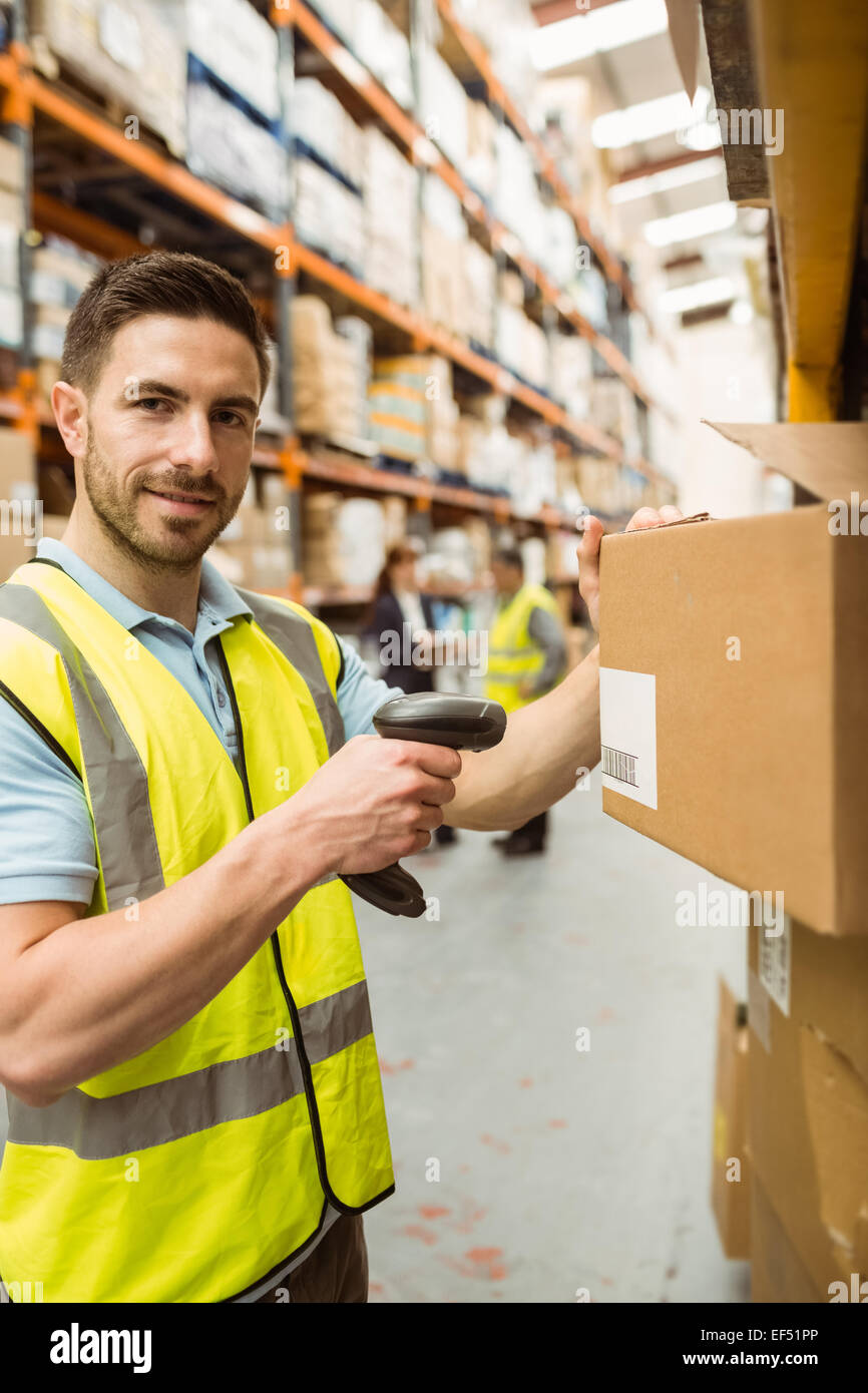 Warehouse worker scanning box while smiling at camera Stock Photo - Alamy