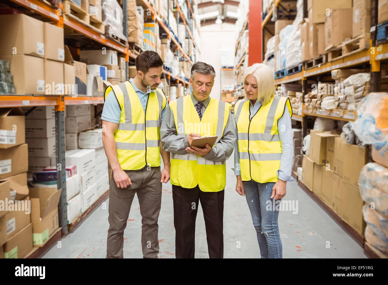 Manager writing on clipboard talking to colleague Stock Photo - Alamy