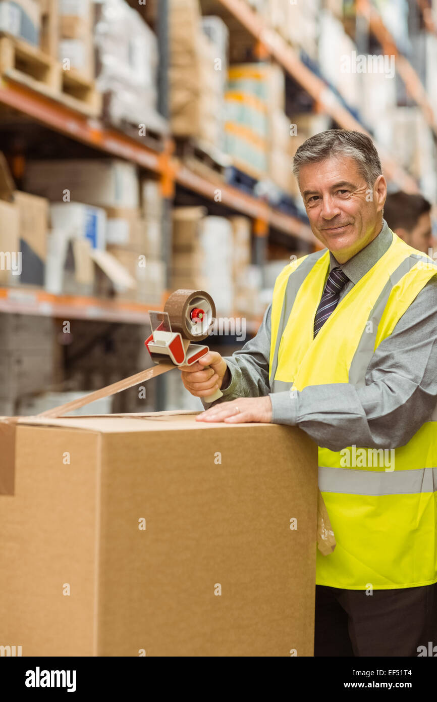 Warehouse worker sealing cardboard boxes for shipping Stock Photo - Alamy
