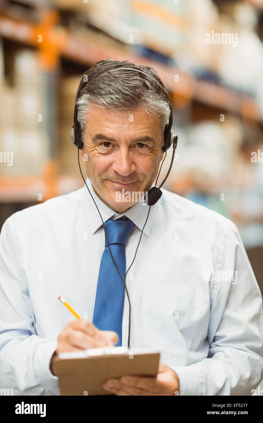 Smiling warehouse manager writing on clipboard Stock Photo - Alamy