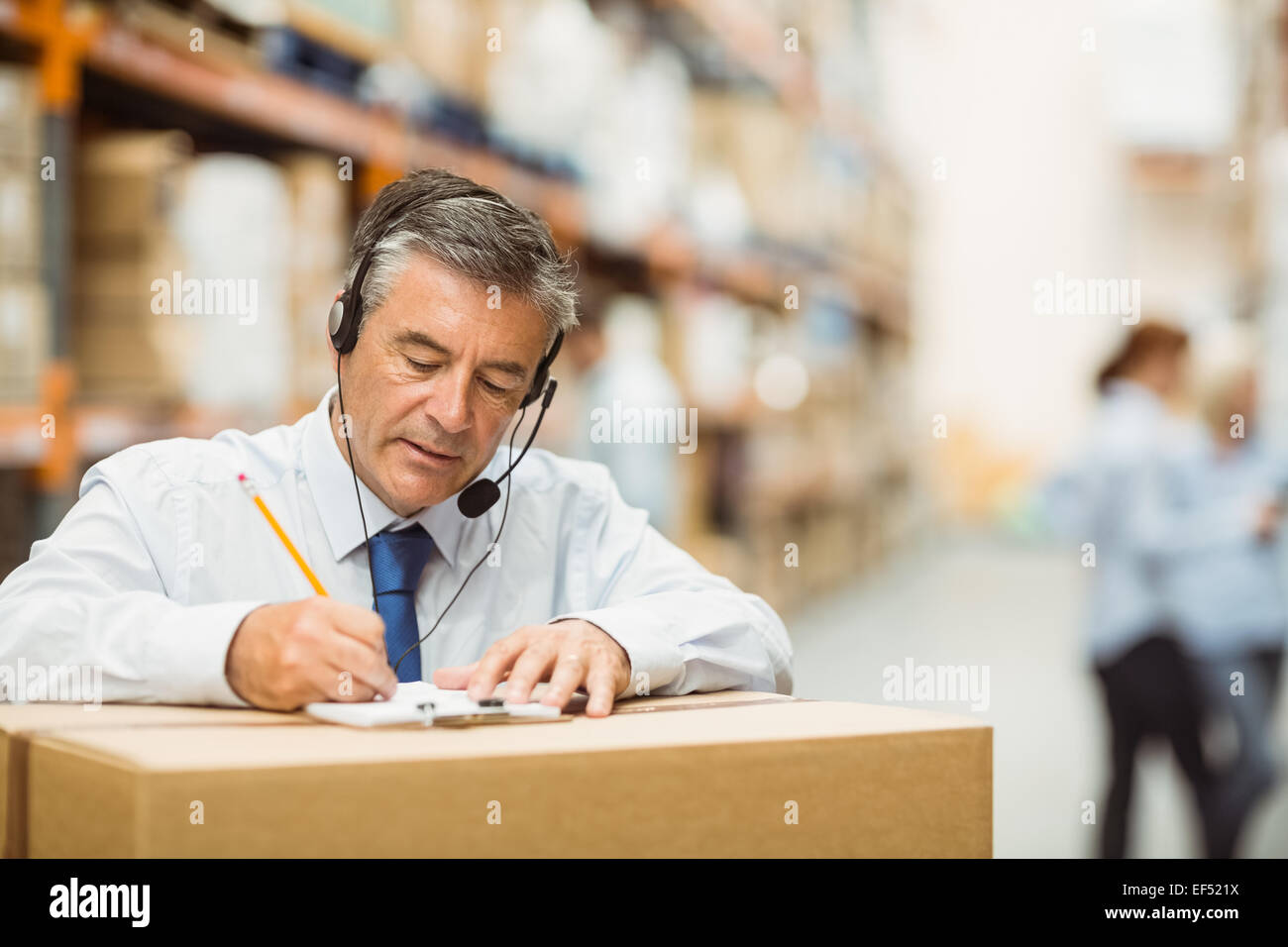 Warehouse manager writing on clipboard Stock Photo - Alamy