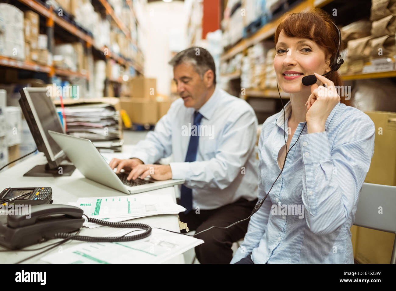 Warehouse manager working at her desk wearing headset Stock Photo - Alamy