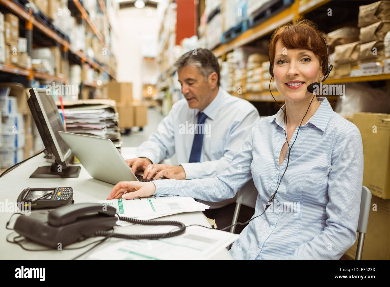 Warehouse manager working at her desk wearing headset Stock Photo - Alamy