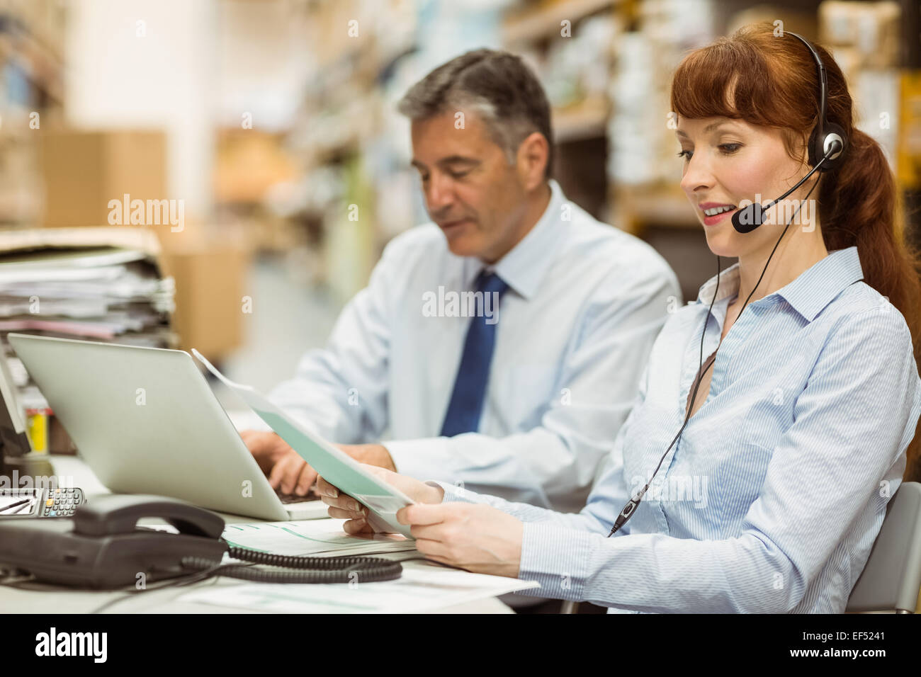 Warehouse manager working at her desk wearing headset Stock Photo - Alamy