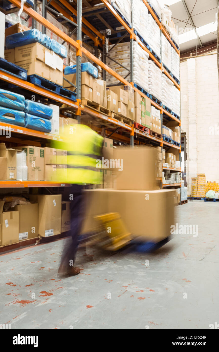 Worker pushing trolley with boxes in a blur Stock Photo - Alamy