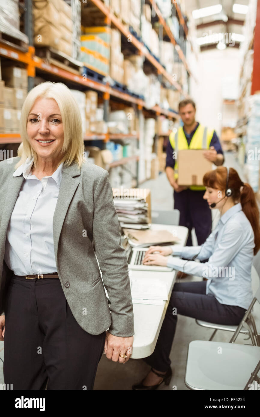 Smiling warehouse manager leaning on desk Stock Photo - Alamy
