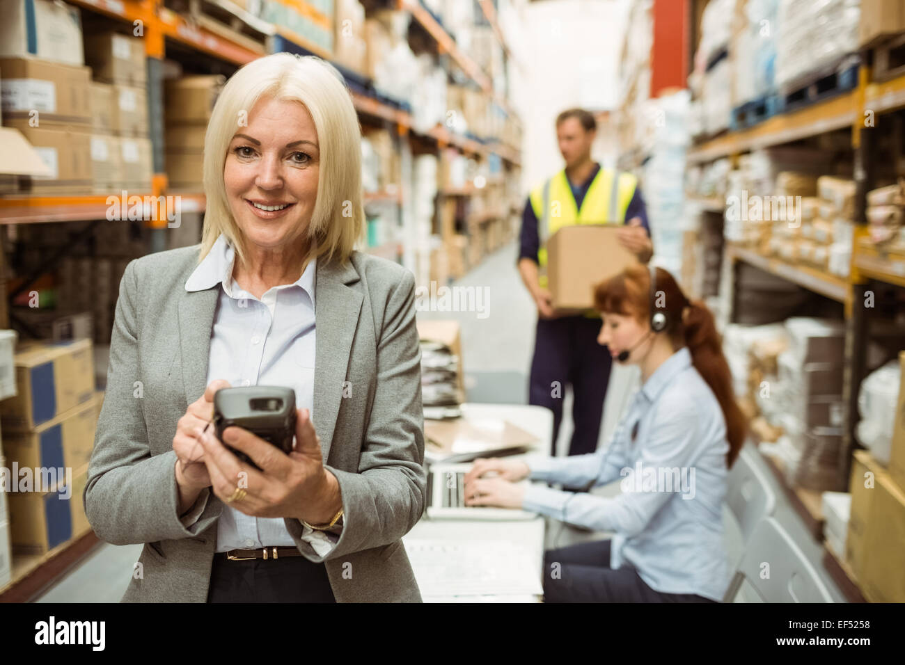 Smiling warehouse manager using handheld Stock Photo - Alamy