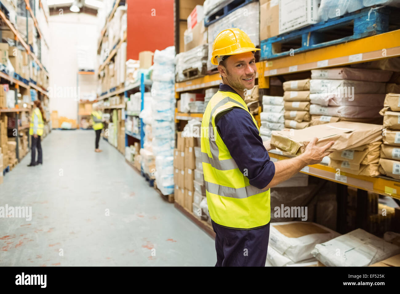 Warehouse worker taking package in the shelf Stock Photo - Alamy