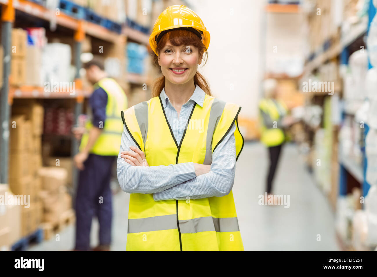 Warehouse manager smiling at camera with arms crossed Stock Photo - Alamy