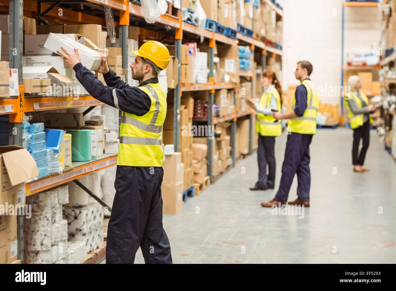 Warehouse worker taking package in the shelf Stock Photo - Alamy