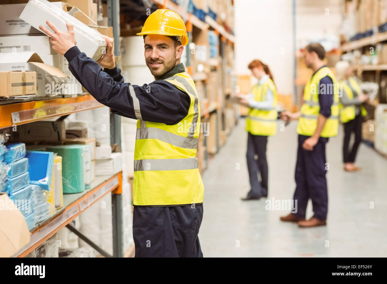 Smiling warehouse worker taking package in the shelf Stock Photo - Alamy