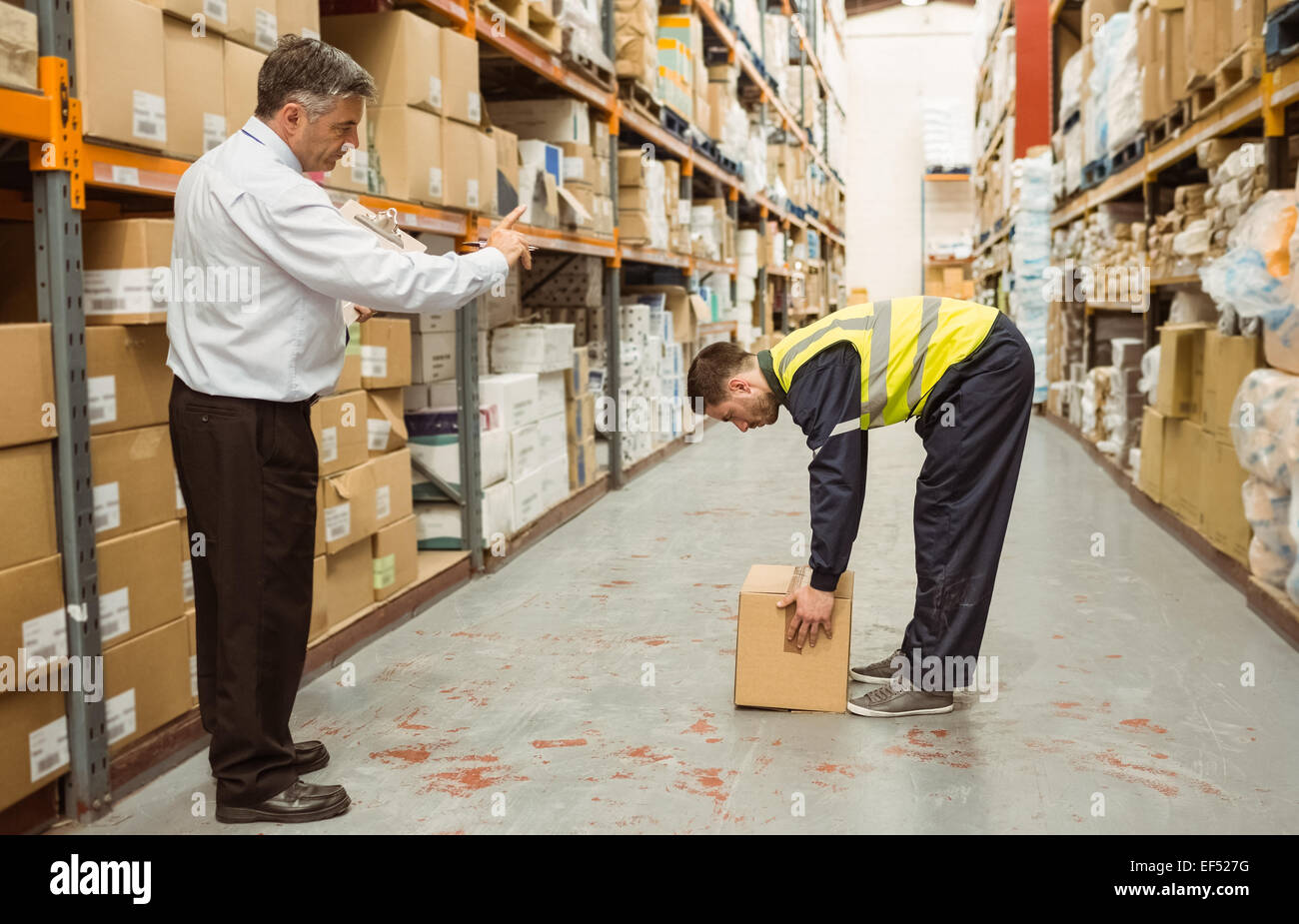 Manager watching worker carrying boxes Stock Photo - Alamy