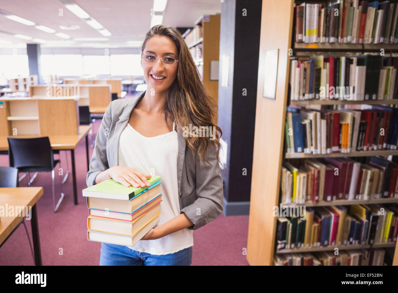 Pretty student smiling at camera in library Stock Photo - Alamy
