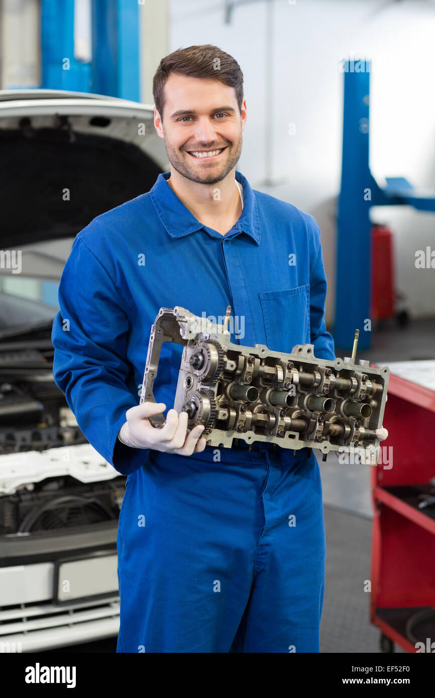 Smiling mechanic holding an engine Stock Photo - Alamy