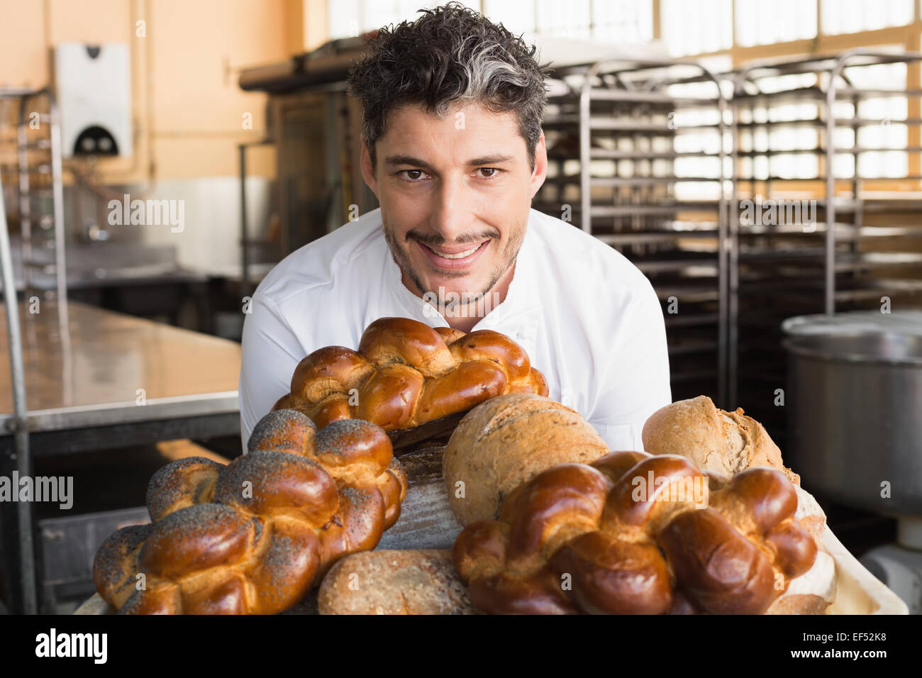 Smiling baker showing board of breads Stock Photo - Alamy