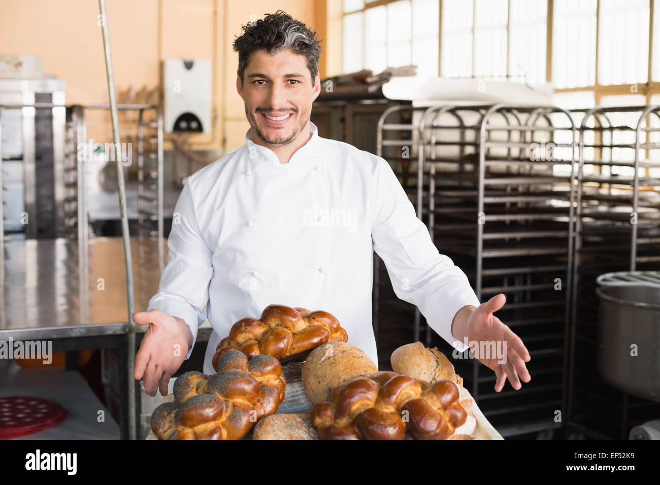 Smiling baker showing board of breads Stock Photo - Alamy