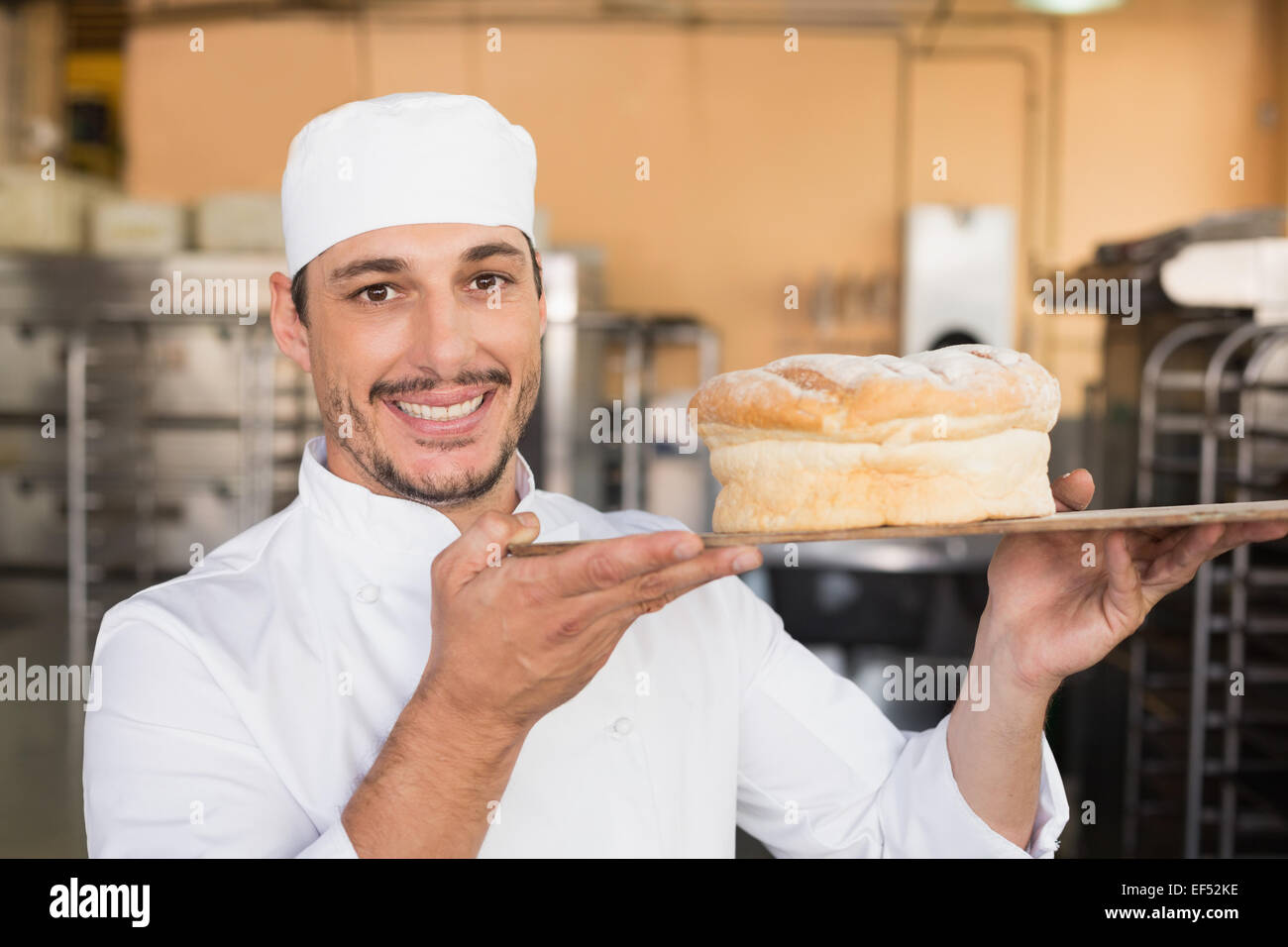 Smiling baker showing loaf of bread Stock Photo - Alamy