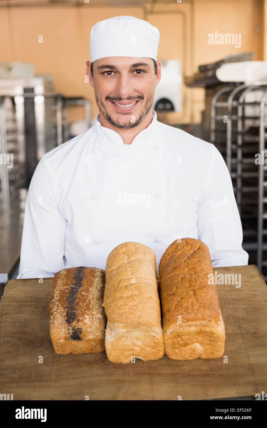 Smiling baker showing loaves of bread Stock Photo - Alamy