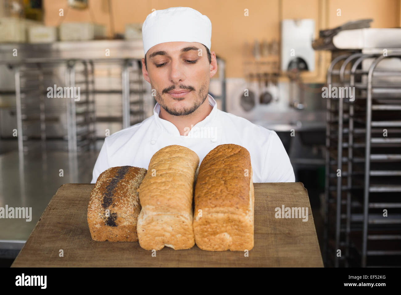 Smiling baker showing loaves of bread Stock Photo - Alamy