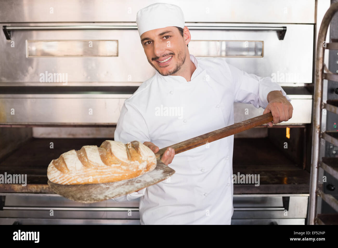 Happy baker taking out fresh loaf Stock Photo - Alamy