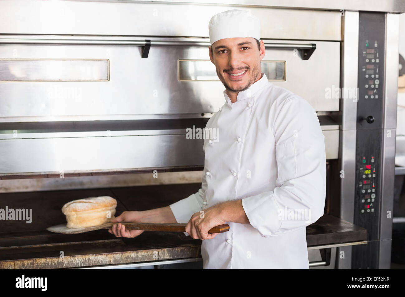Happy baker taking out fresh loaf Stock Photo - Alamy
